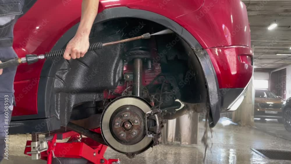 Washing the rear suspension of an SUV with a high-pressure water jet at ...