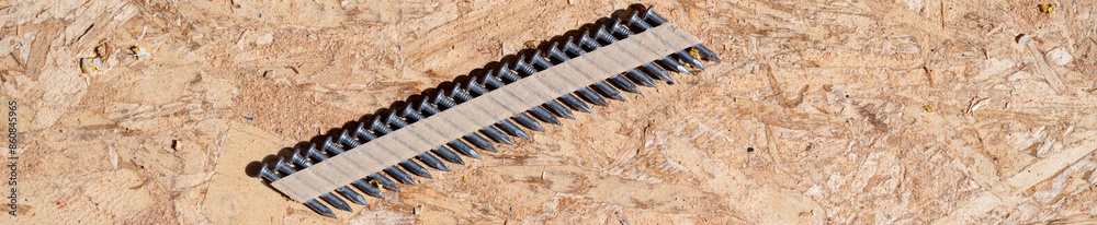 Construction background, collated nail gun nails, connected with paper ...