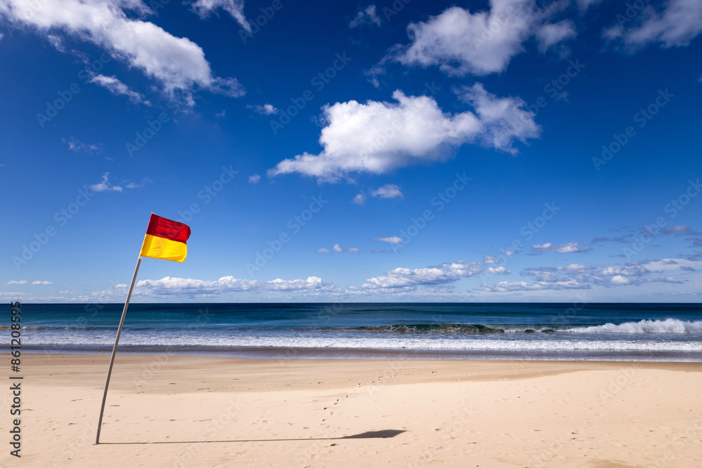 Australian surf life saving flag blowing in the breeze on a sandy ...