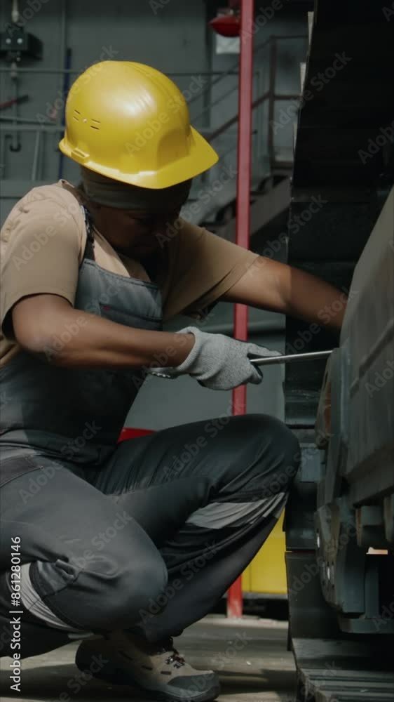 Vertical shot of Black female mechanic in workwear and hardhat using ...
