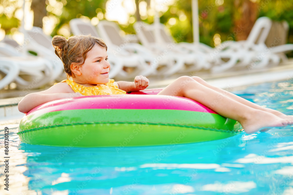Happy little girl with inflatable toy ring float in swimming pool ...