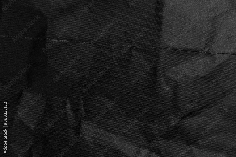 Crumpled black paper surface, highlighting the interplay of light and ...