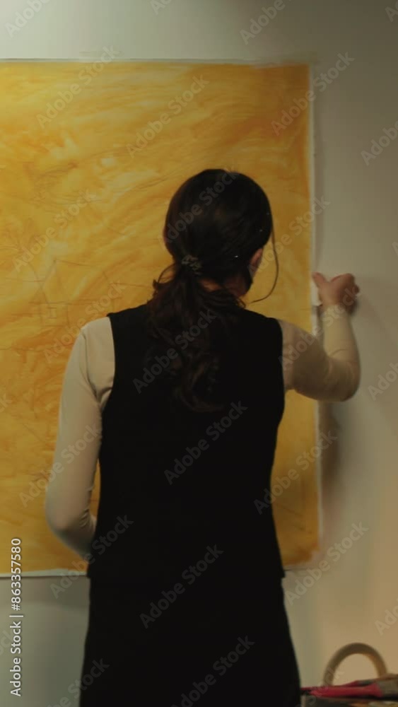 Back view of female artist hanging painting in gallery before ...