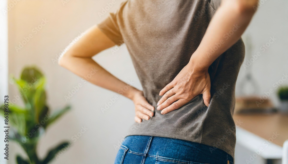 woman's hand holding her lower back, signifying back pain. The image is ...
