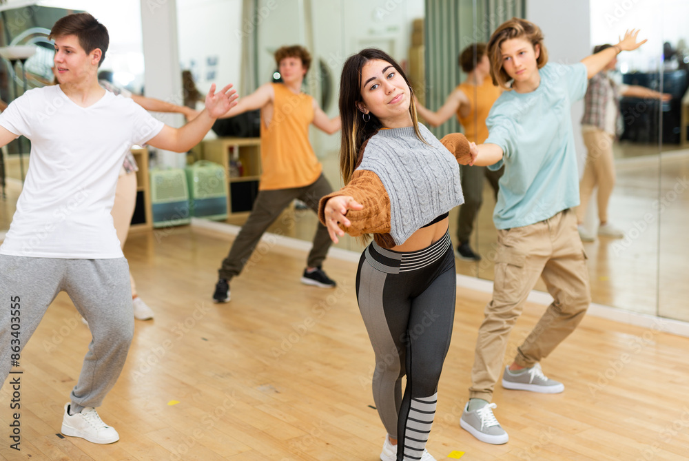 Cheerful hispanic teenage girl learning to dance vigorous jive in pair ...