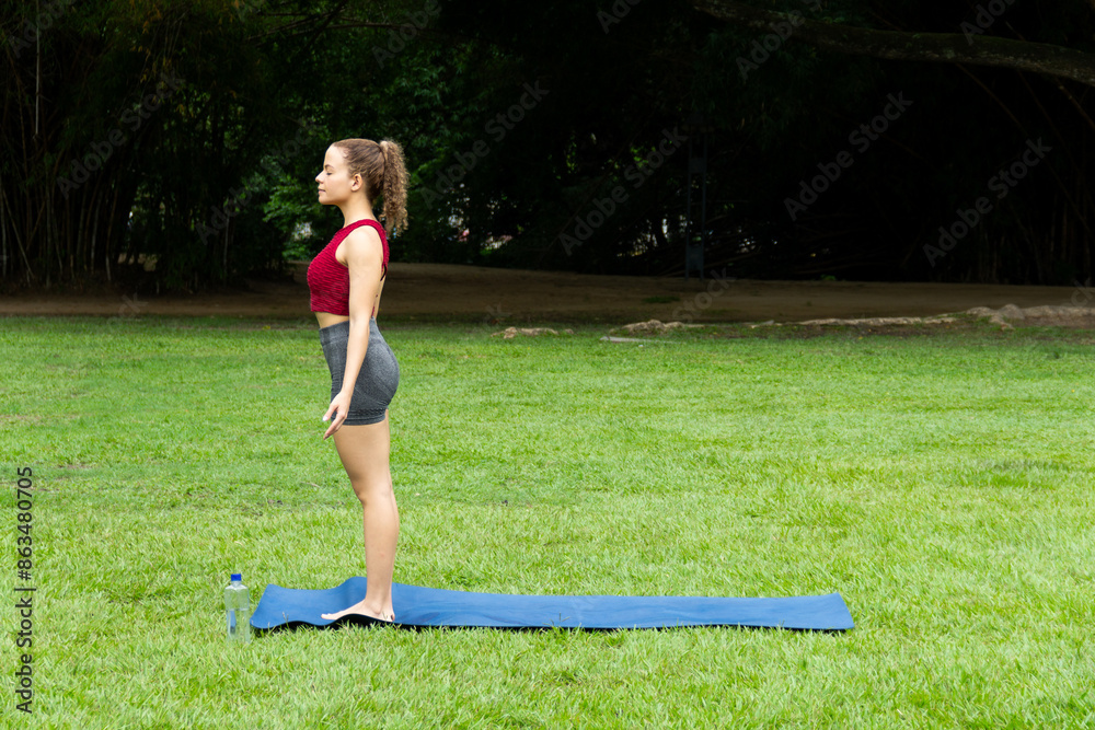 Side view of beautiful slim woman standing in mat doing yoga and zen ...