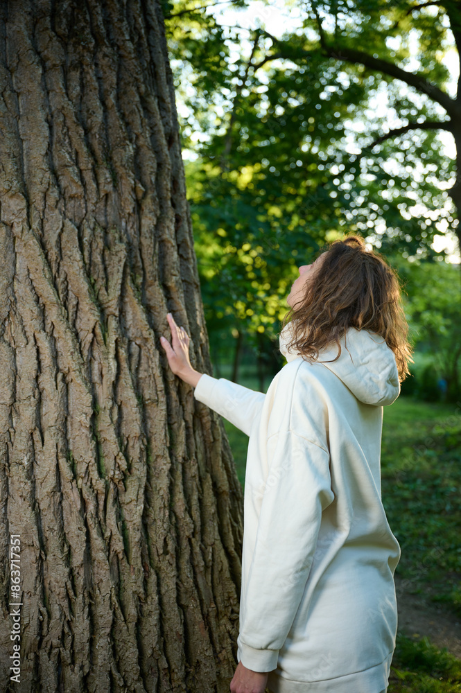 Pretty woman leaning on the old tree. Female hugging huge tree trunk ...