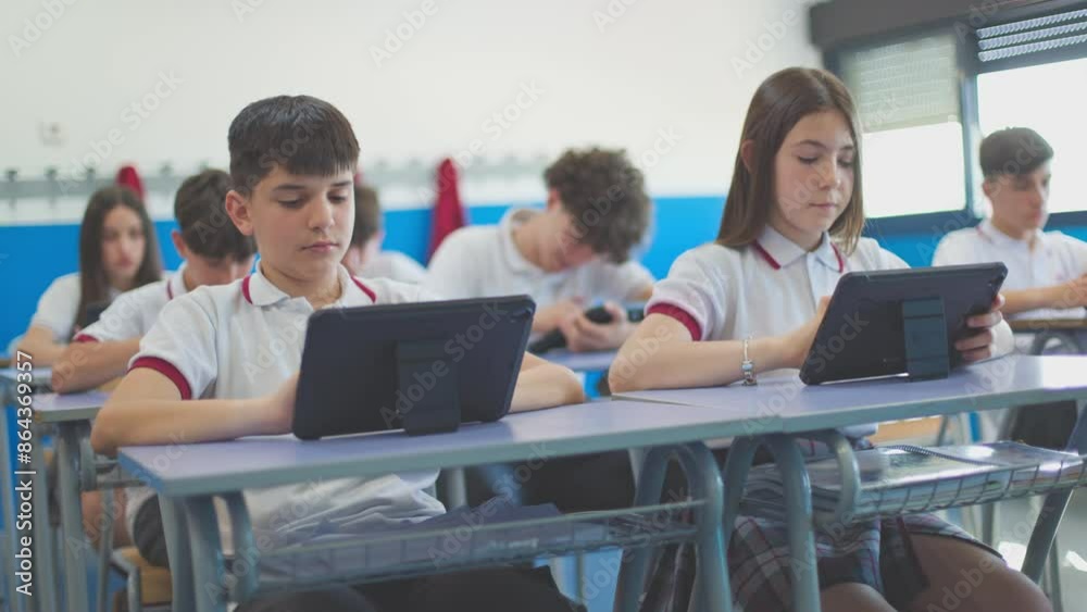 Focused students in uniform using tablets in a modern classroom. Stock ...