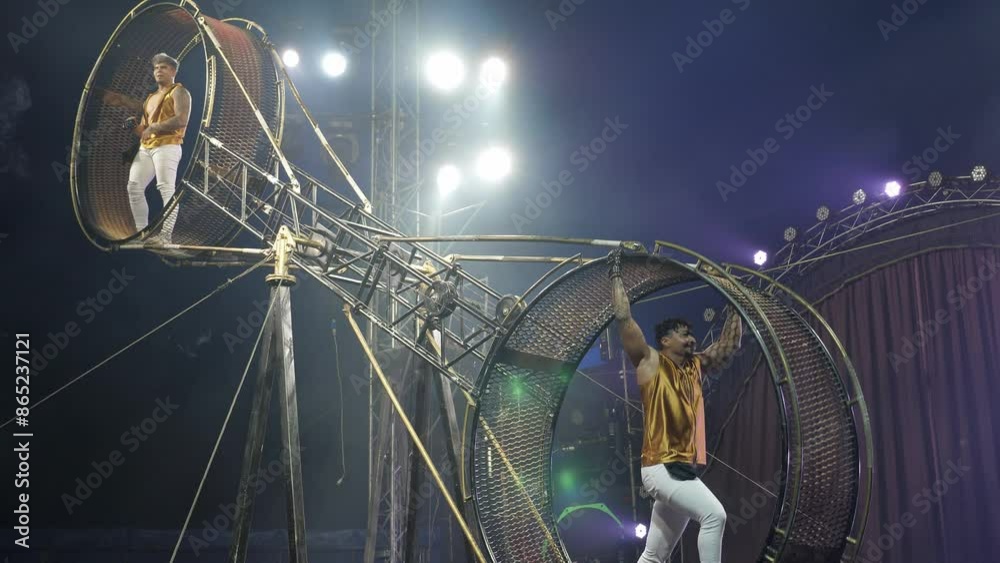 Portrait of brave acrobats on the rotating wheel of death under the ...