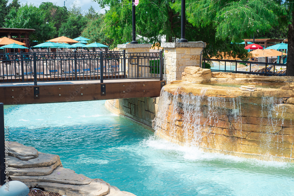 Pedestrian bridge across lazy river turquoise clean water, curved line ...