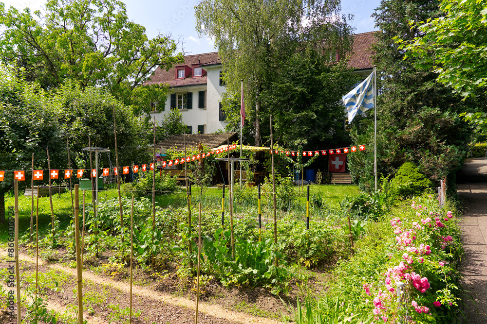 Garden plot with decoration of Swiss flags and flying flag of Swiss ...