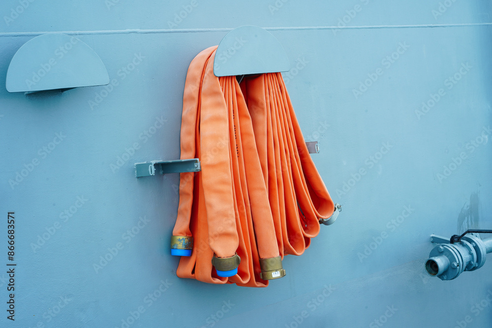 Orange fire hose reel was attached to the blue wall in old military war ...