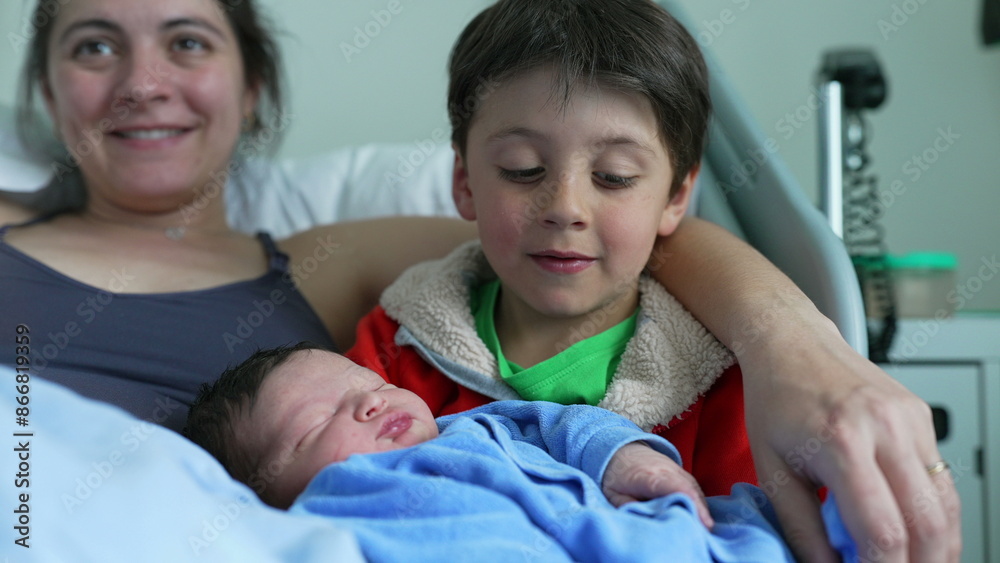 Mother watches lovingly as older sibling cradles newborn baby ...