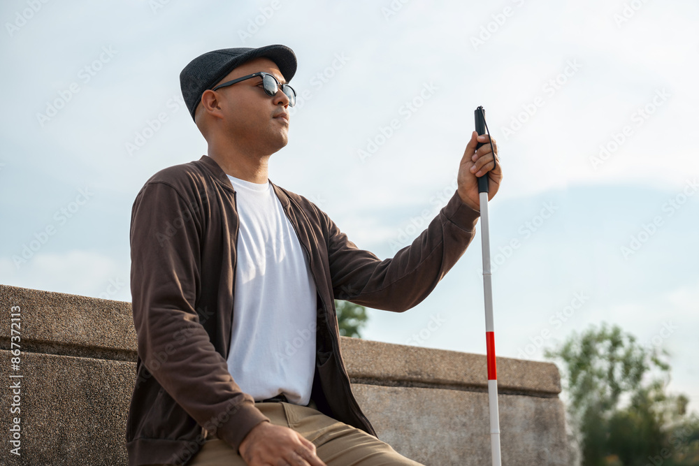 Young asian blind man sitting outside holding walking stick Visually ...
