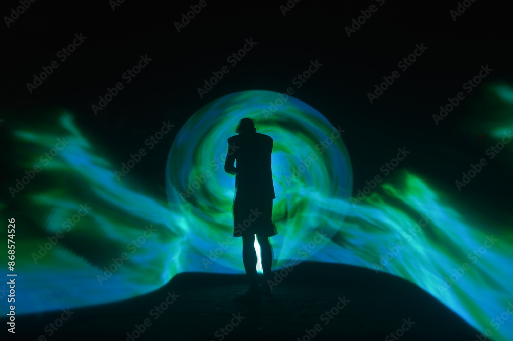 One person standing alone against a Colourful circle light painting as ...