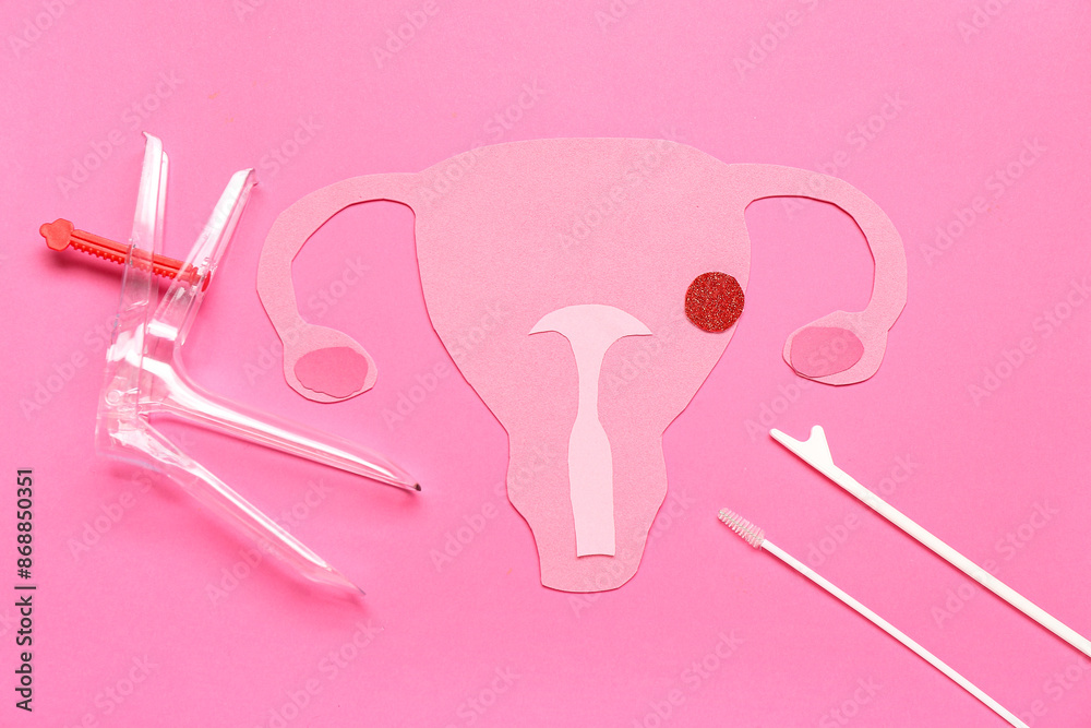 Paper uterus with gynecological speculum and pap smear test tools on ...