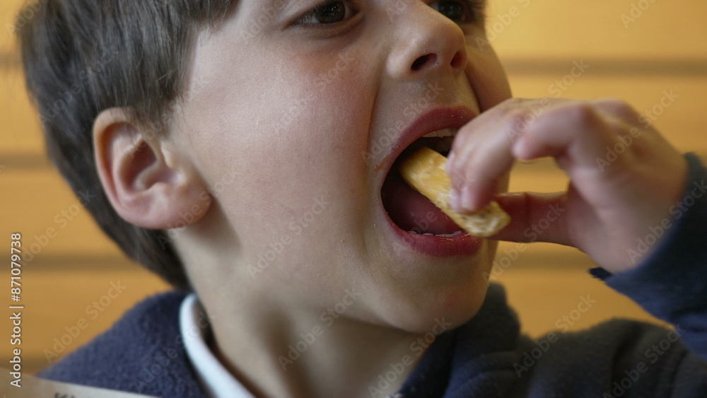 Boy quickly pulls away a hot fry from his mouth, expressing surprise ...