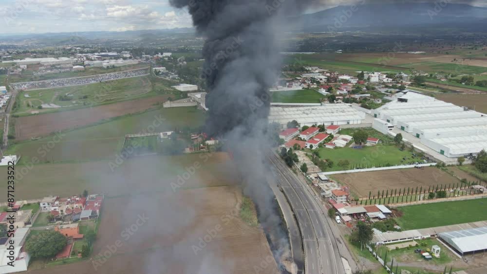 large plume of black smoke coming out from a fire explosion of a fuel ...