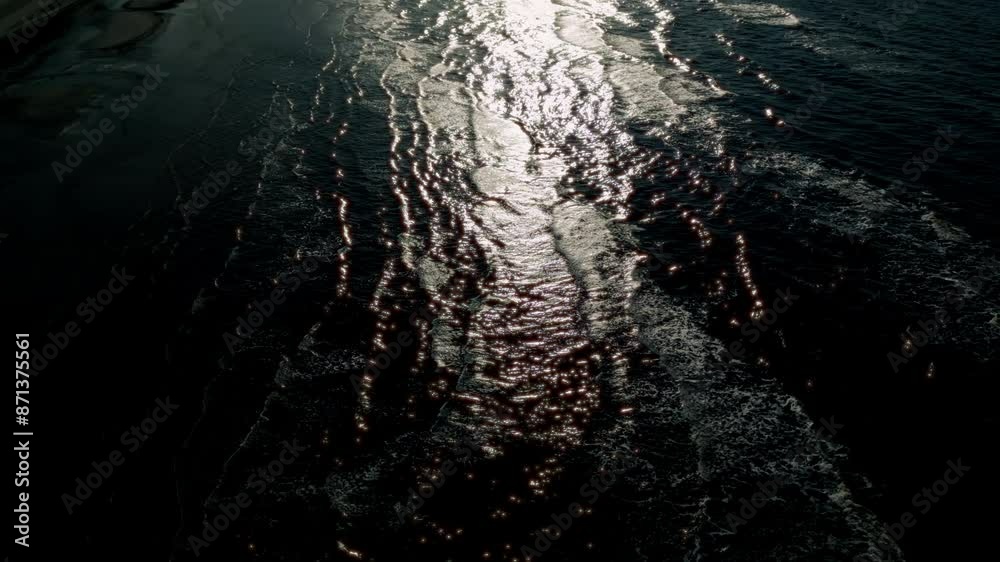 Dark black water with a mysterious wave pattern and light reflections ...