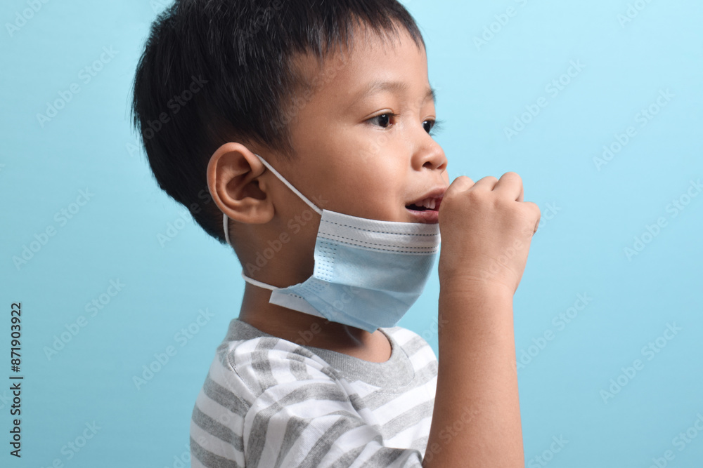 Asian Boy wearing health mask is coughing isolated on blue background ...