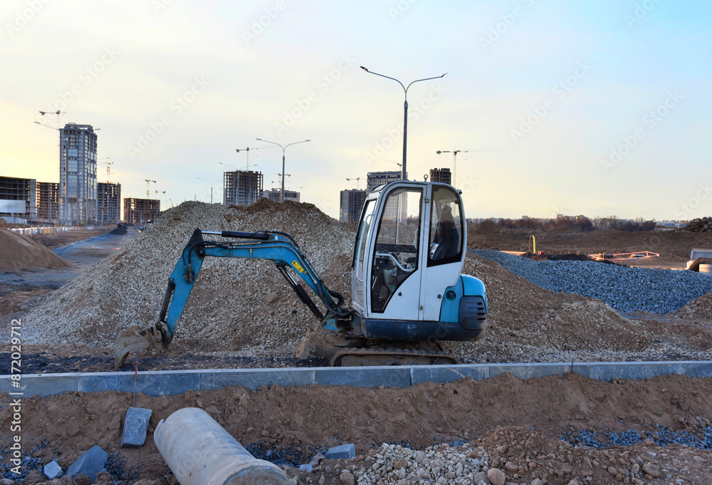Mini excavator on road construction. Screeding sand for installing ...