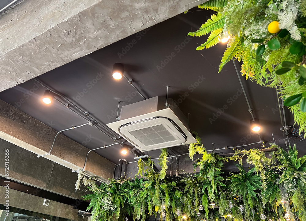 Modern ceiling mounted air conditioning unit surrounded by green plants ...