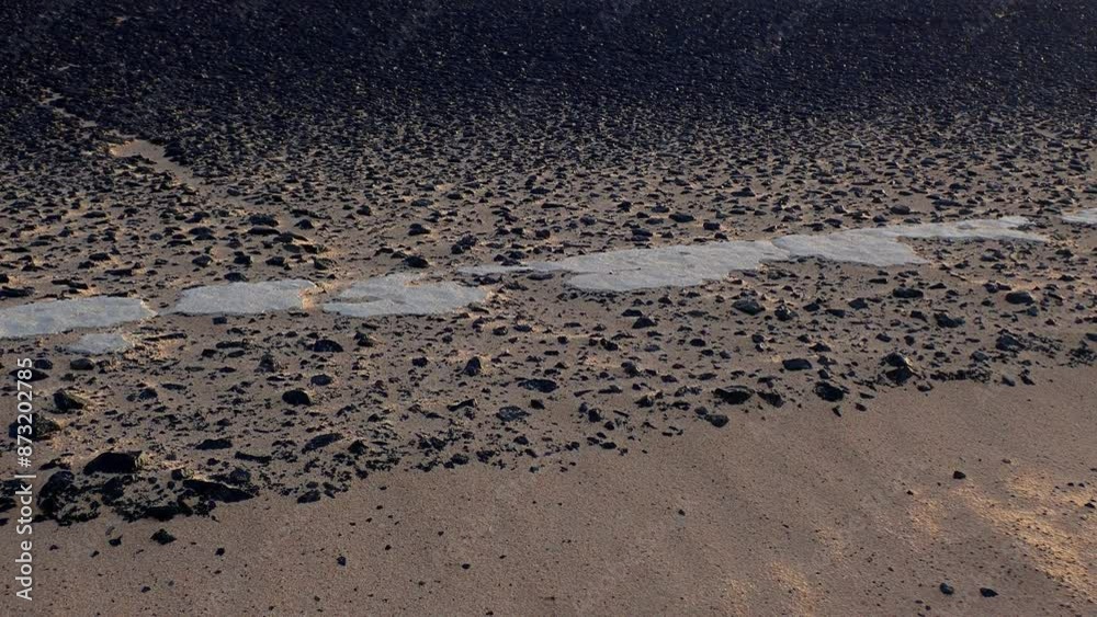 Cracked and half-buried in sand roadside on a European desertic island ...