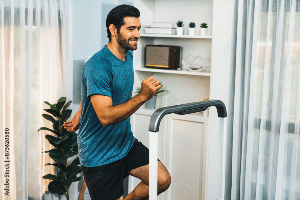 Athletic and sporty man running on running machine during home body ...