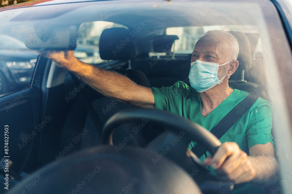 Caucasian male doctor driving a car. Mature nurse driving home after a ...