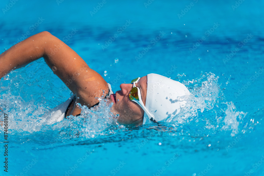 Female swimmer in white swim cap and goggles performing freestyle ...