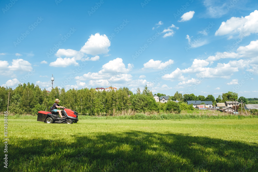 Man on lawn tractor mowing lawn on backyard. The red rider. The ...