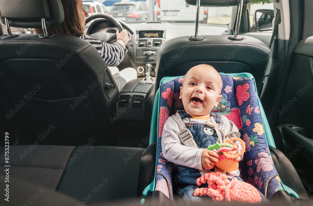 Portrait of laughing baby in car seat while Mother driving a passenger ...