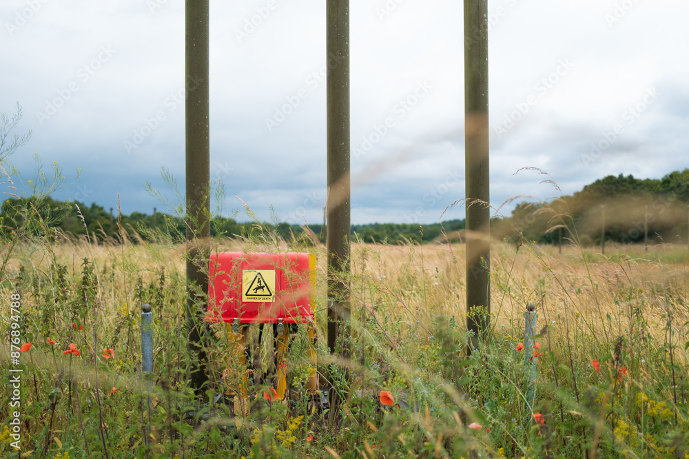 Bright red electrical control box with warning sign seen next to three ...