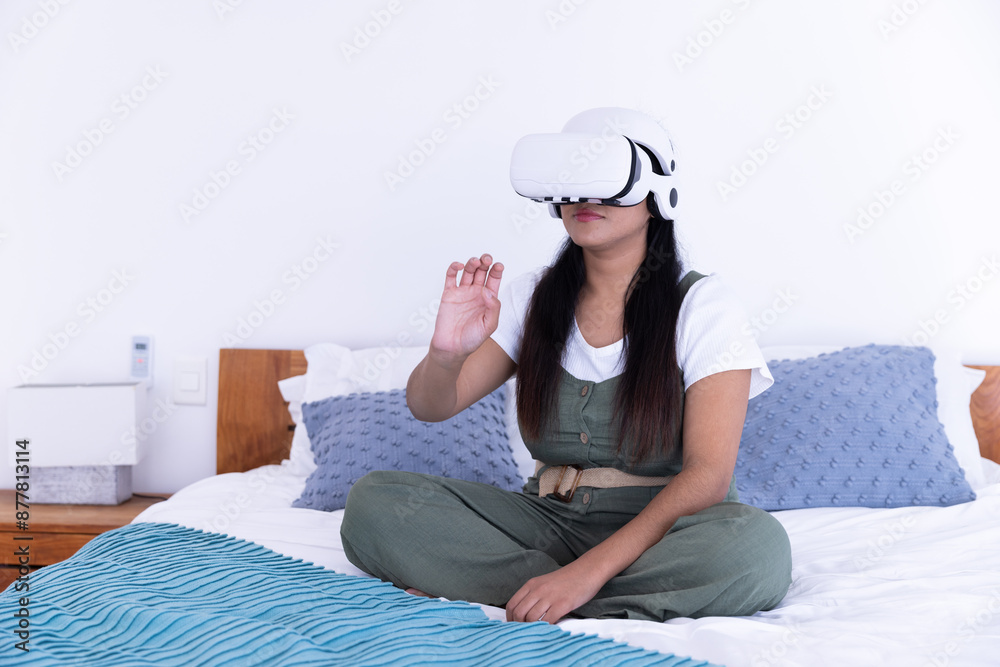 Using VR vr vr headset, woman sitting on bed and interacting with ...