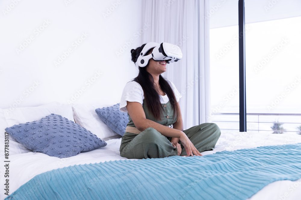 Using VR vr vr headset, woman sitting on bed, enjoying virtual reality ...