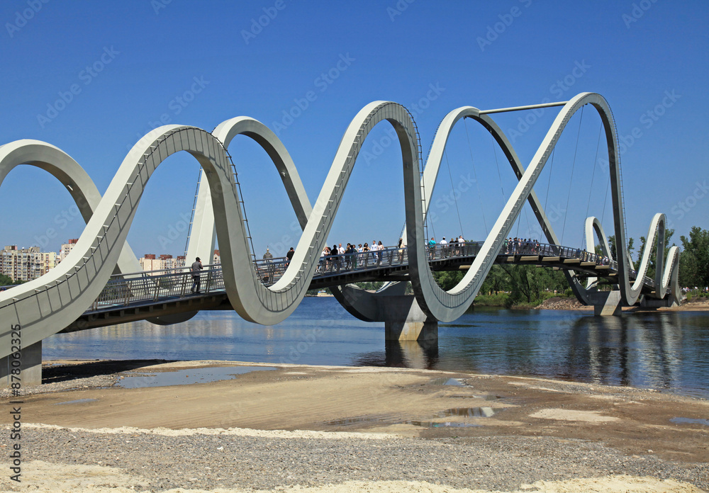 Modern artistic wave shaped bridge over the river. New innovative ...