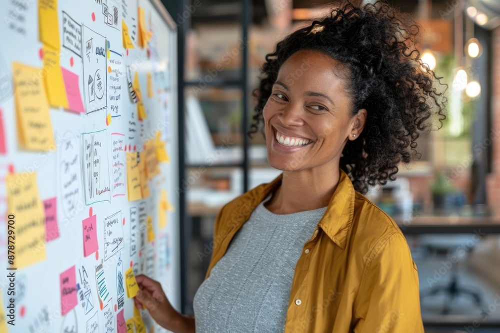 A woman smiles with confidence as she adds a sticky note to a ...