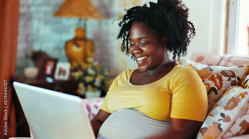 Happy pregnant black woman working remotely on laptop at home ...