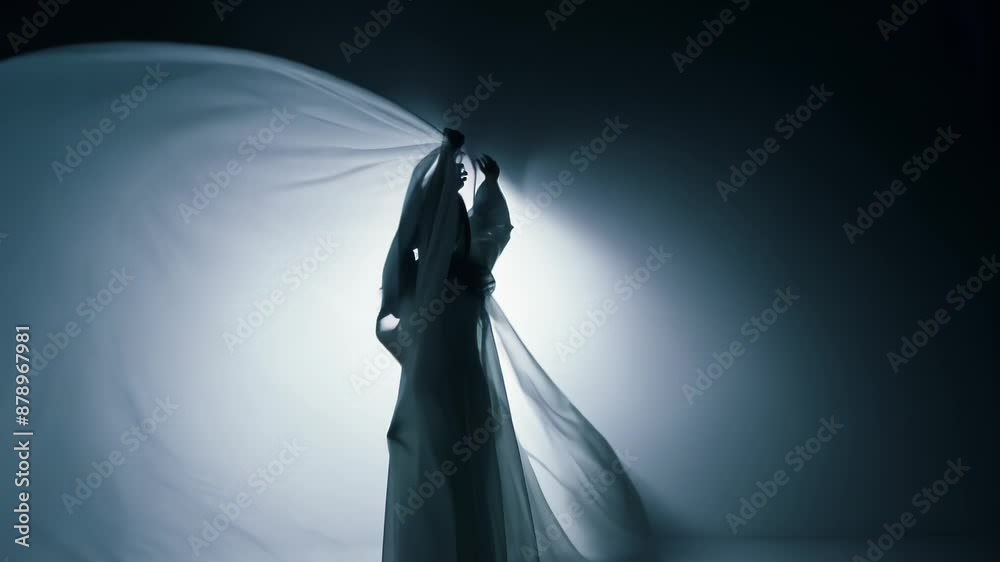 Ghostly figure draped in billowing white fabric emerges from darkness. Faceless form with ...