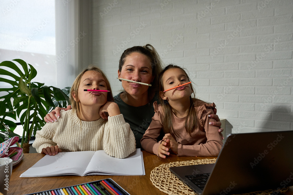 Homework fun: Mother and daughters, seated at the dining table, make ...