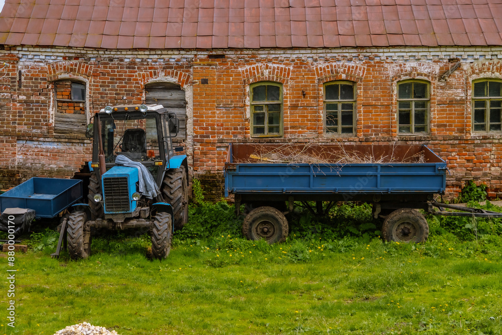 An old rusty Soviet-era tractor is parked in the backyard. Repair of ...