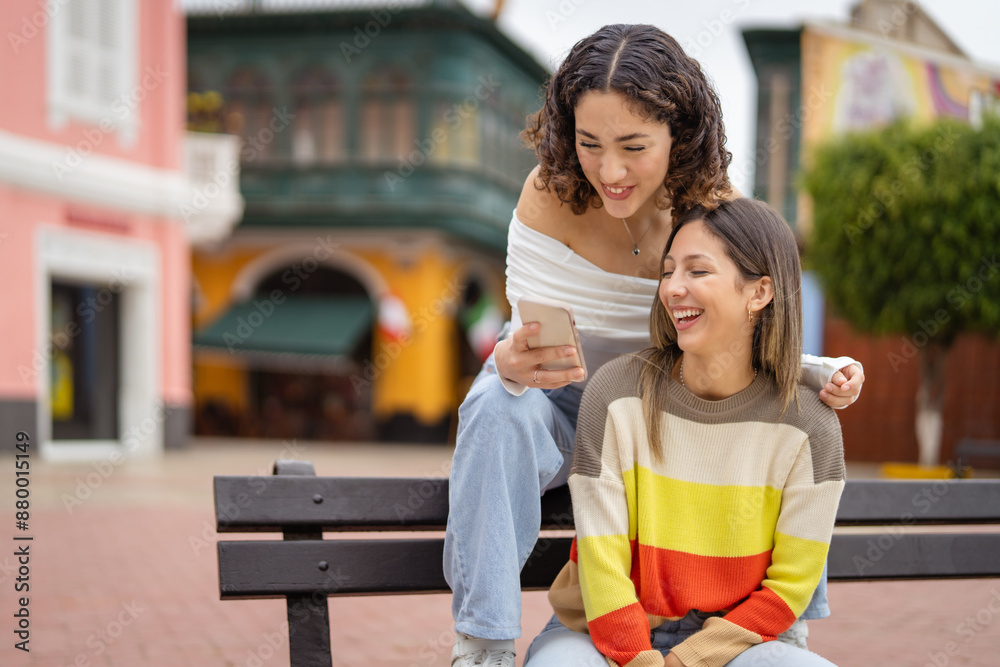Two friends laughing while watching something funny on mobile phone ...