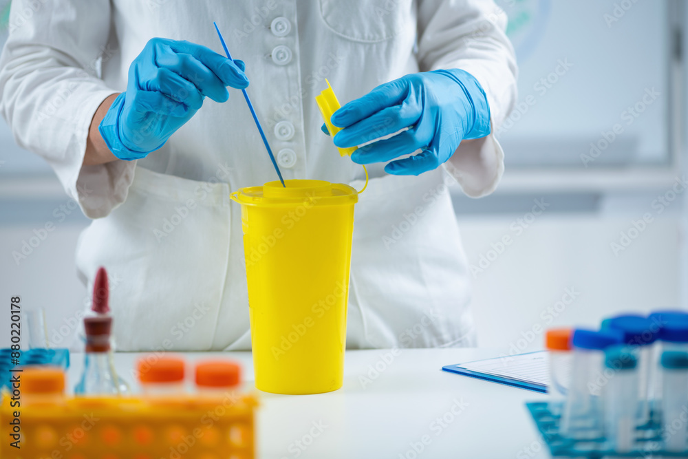 Disposing of laboratory consumables in hazardous waste container. Stock ...
