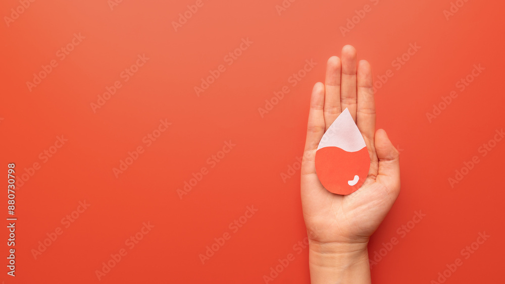 Human hand holding blood drop shape with blood level on red background ...