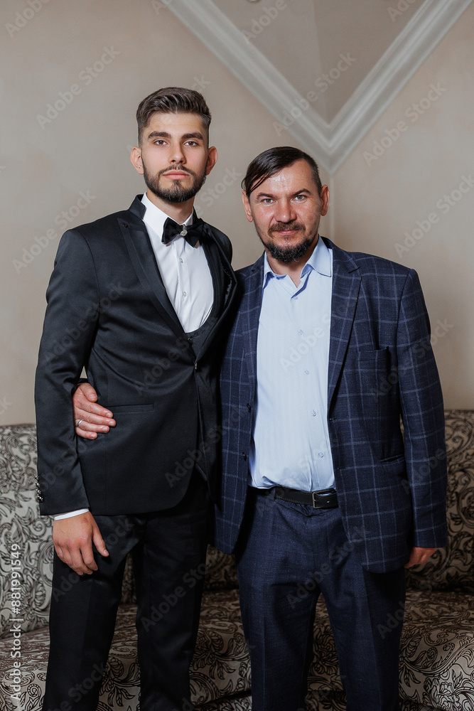 Two men in suits are posing for a picture. One of them is wearing a tie ...