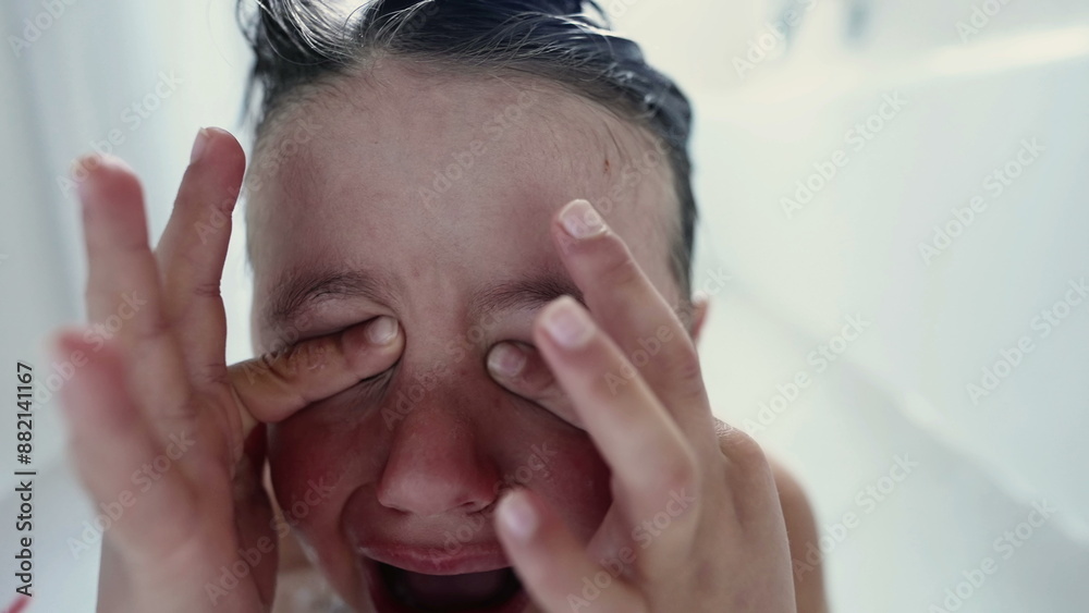 Boy in bathtub crying with hands covering eyes, capturing intense ...