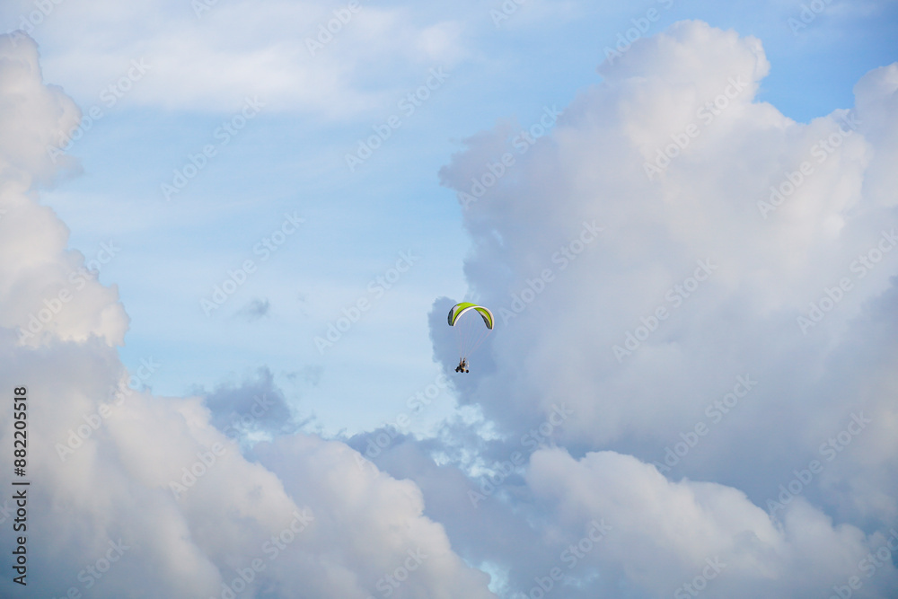 Paraglider with motor flying in the cloudy sky. Tiny cloud floating ...