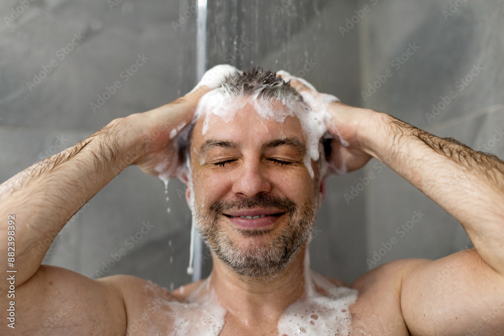 Portrait of handsome middle aged man taking shower, standing under ...