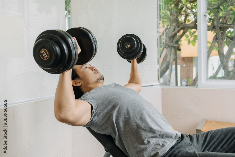 Fitness asian Thai man lifting heavy weight dumbbells, lying on bench ...