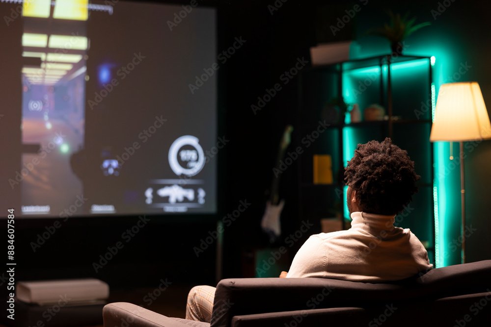 Gamer in front of ultrawide smart TV, watching first person shooter ...